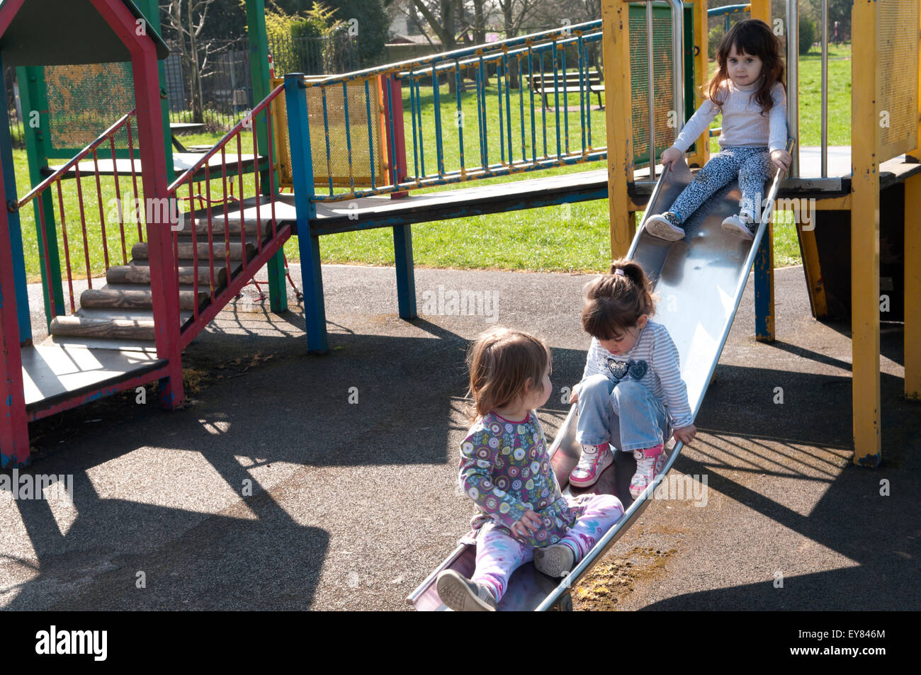 Three little girls playing together on a slide Stock Photo - Alamy