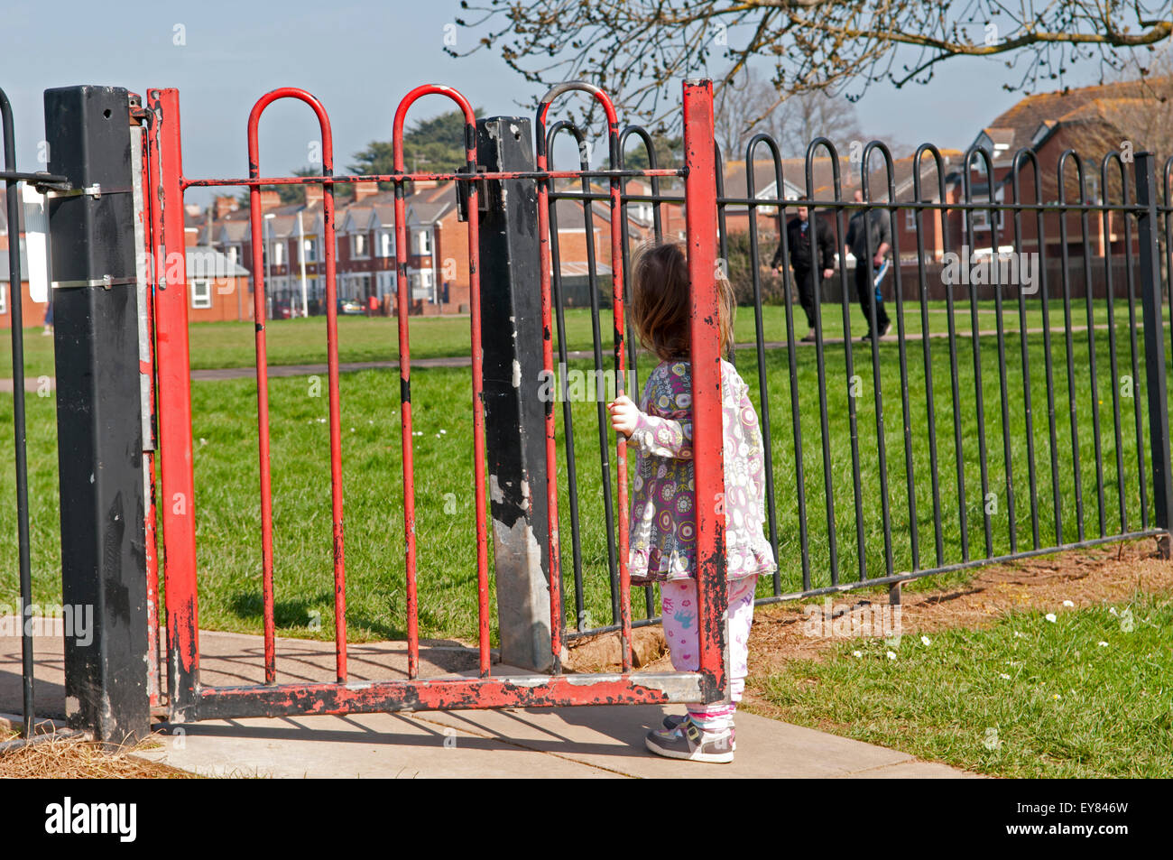 Toddler standing by playground gate Stock Photo - Alamy