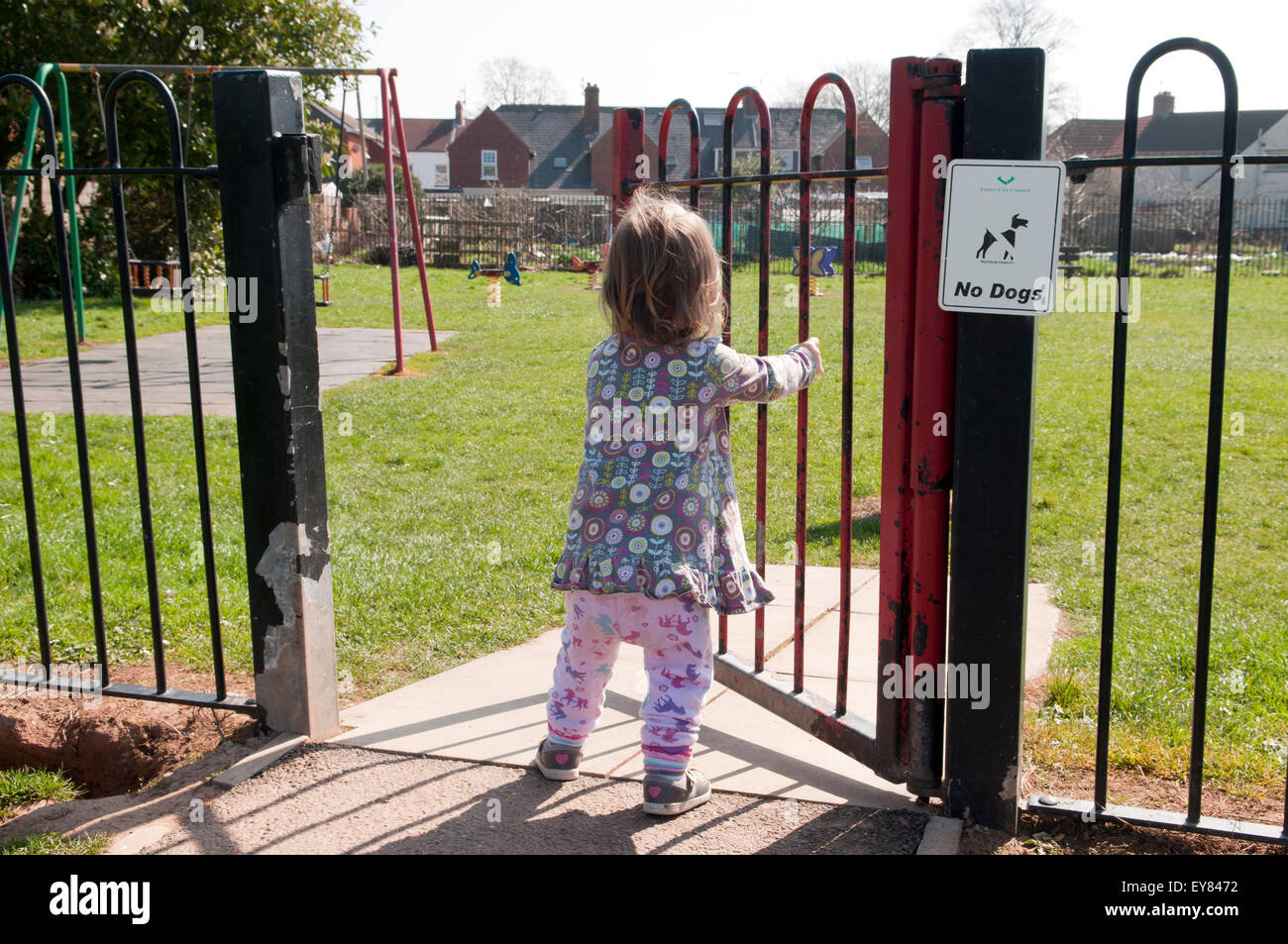 Toddler opening playground gate Stock Photo - Alamy