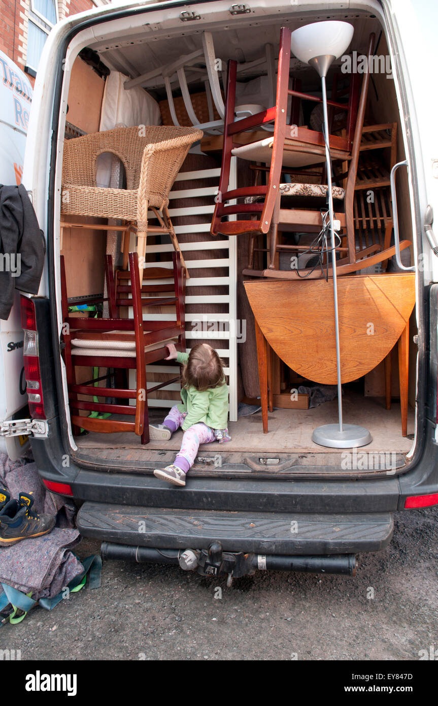 Little girl sitting on the back of a removal van looking up at all the ...