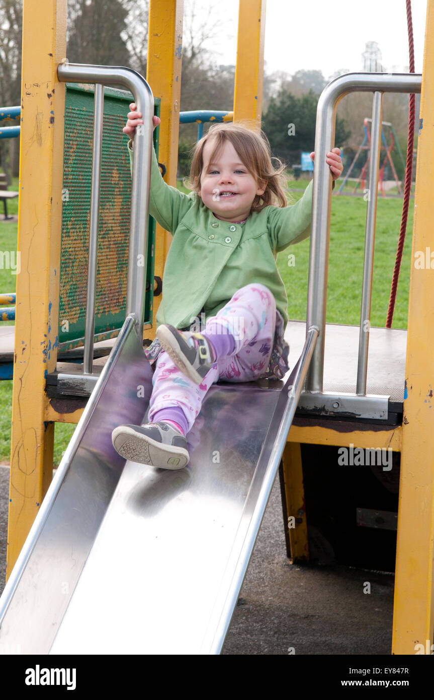 Happy little girl smiling sitting on a slide Stock Photo - Alamy