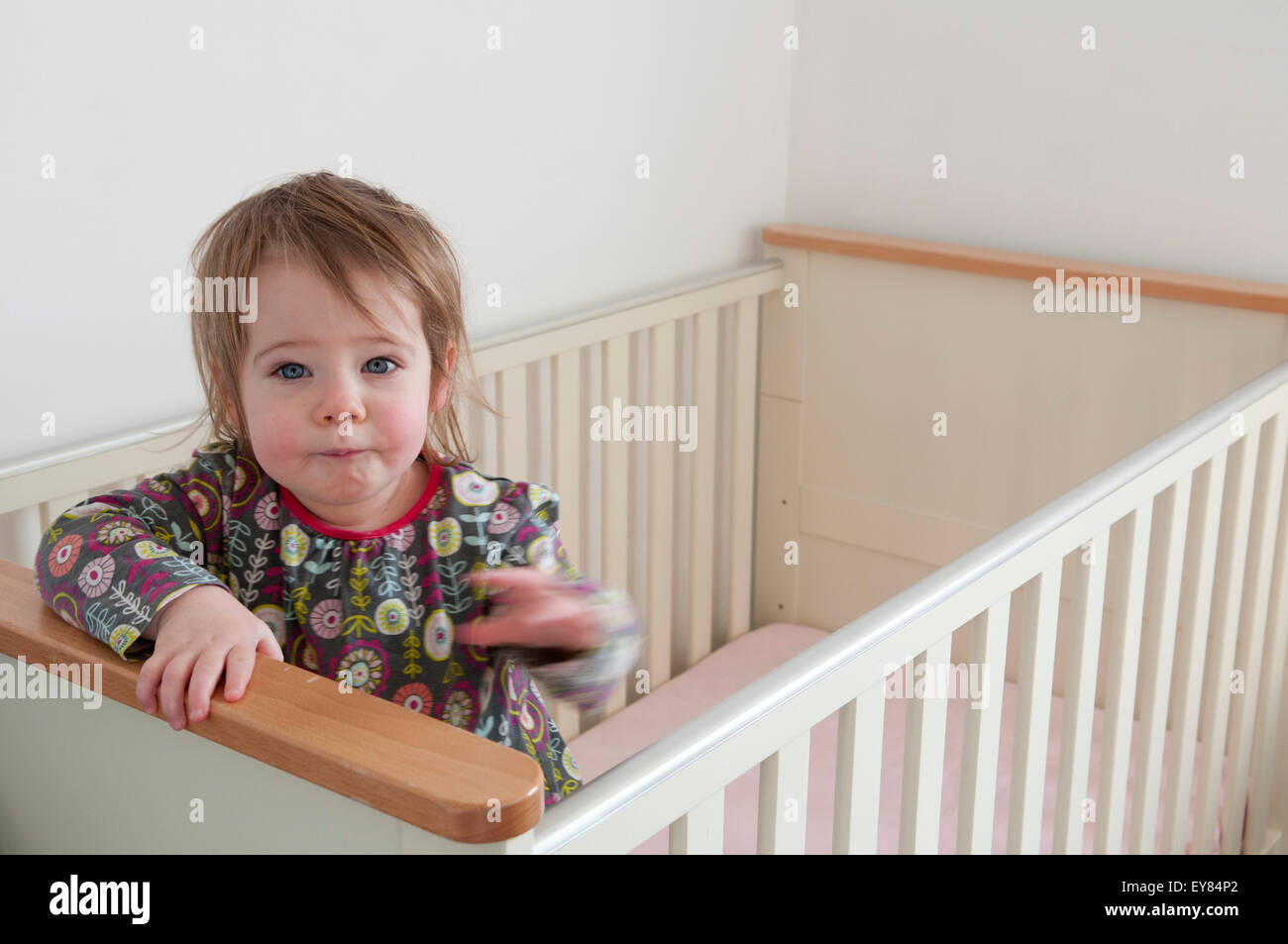 Little girl standing inside her cot Stock Photo - Alamy