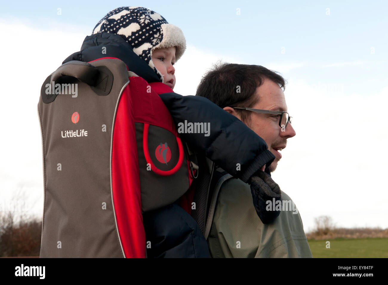 Side view of a baby in an infant carrier being carried by her father ...