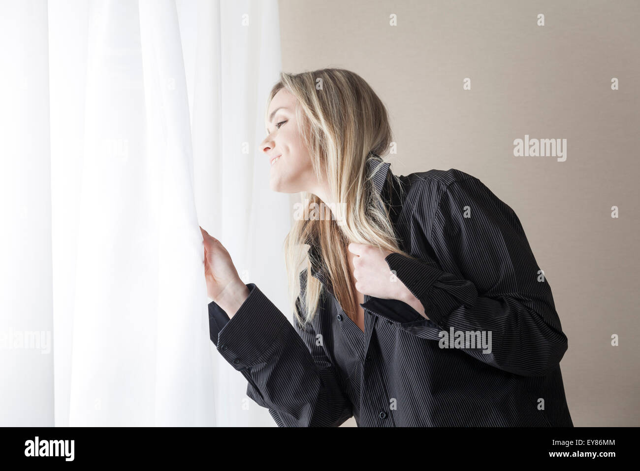 Young woman looking out of window Stock Photo - Alamy