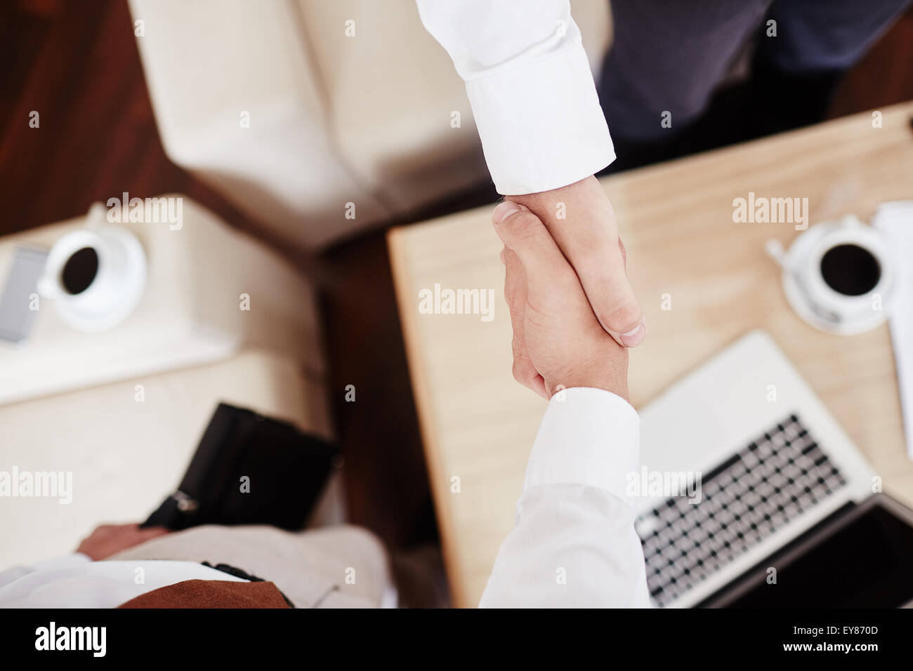 Businessmen greeting one another over workplace Stock Photo - Alamy
