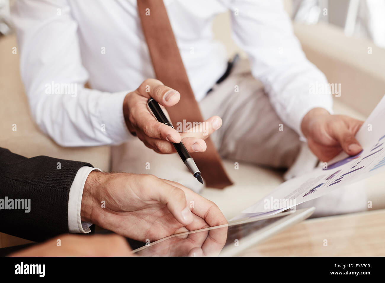 Male employees discussing paper and electronic documents Stock Photo ...