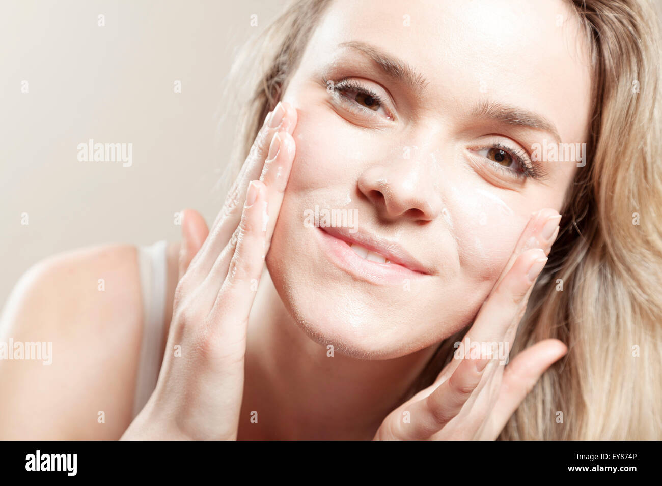 Young woman applying lotion on face, close-up Stock Photo - Alamy