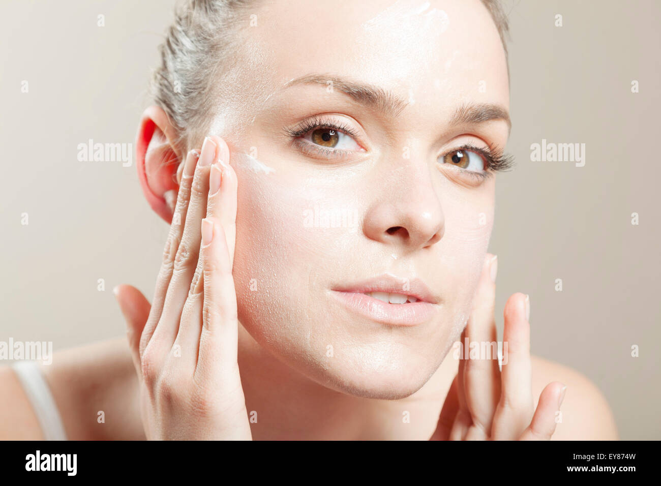 Young woman applying lotion on face, close-up Stock Photo - Alamy
