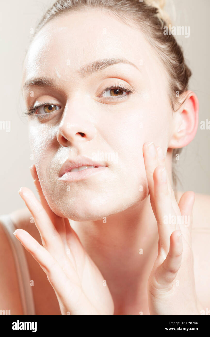 Young woman applying lotion on face, close-up Stock Photo - Alamy