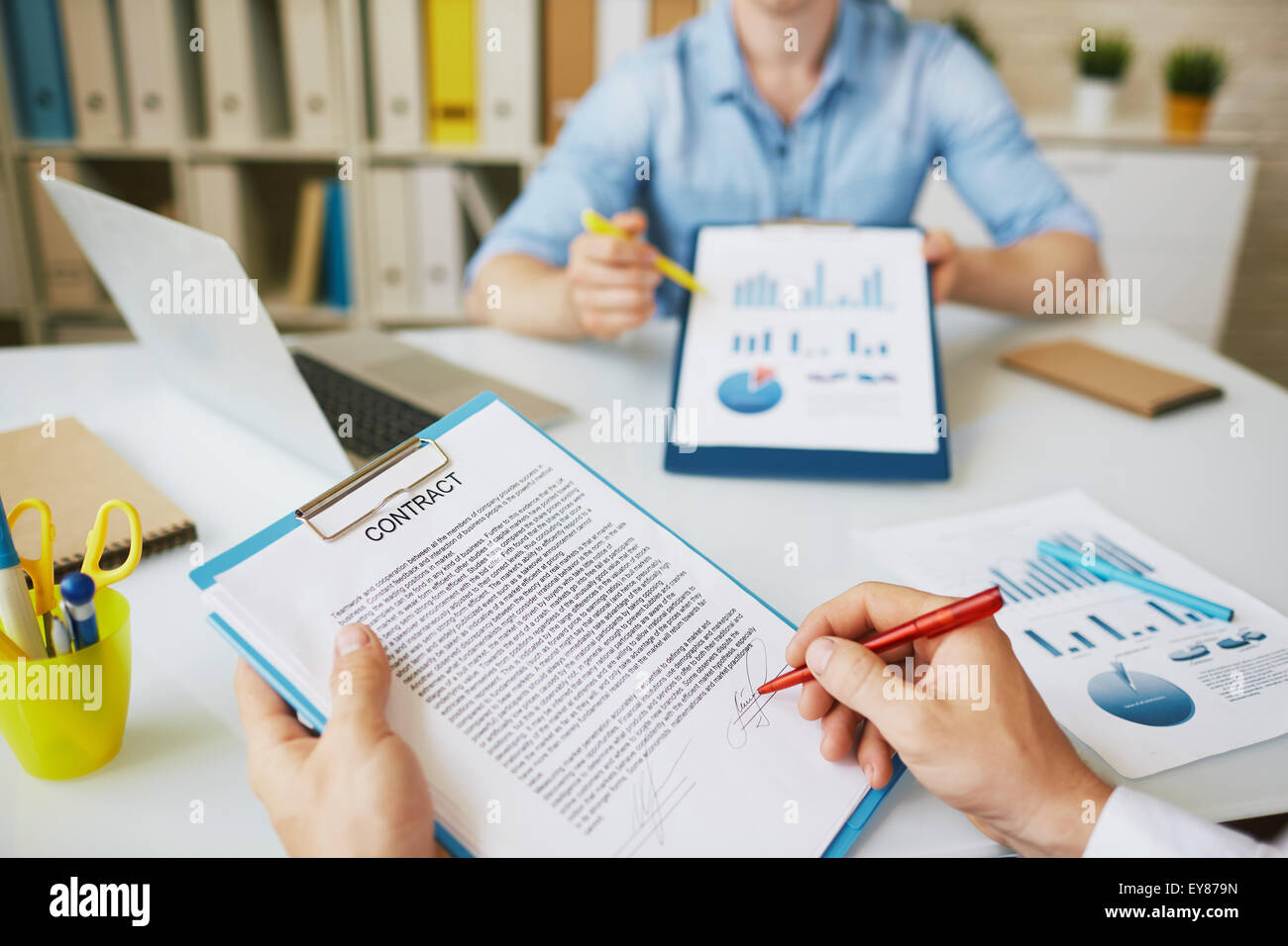 Male employee signing business agreement in working environment Stock ...
