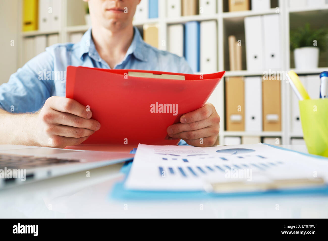 Businessman holding red folder over workplace Stock Photo - Alamy