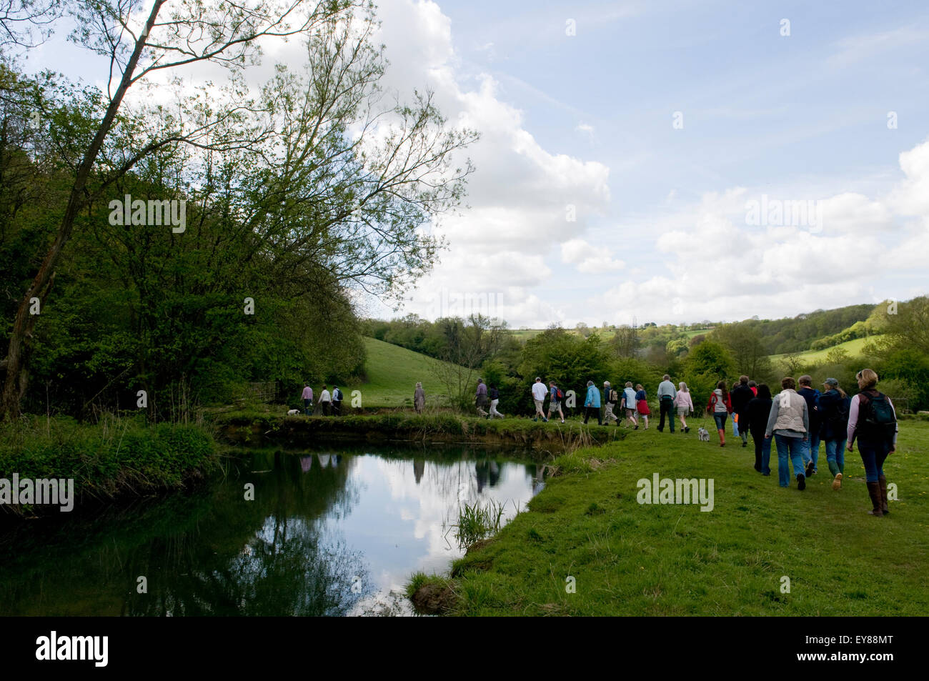 Rear view of ramblers walking across a field beside a river Stock Photo ...