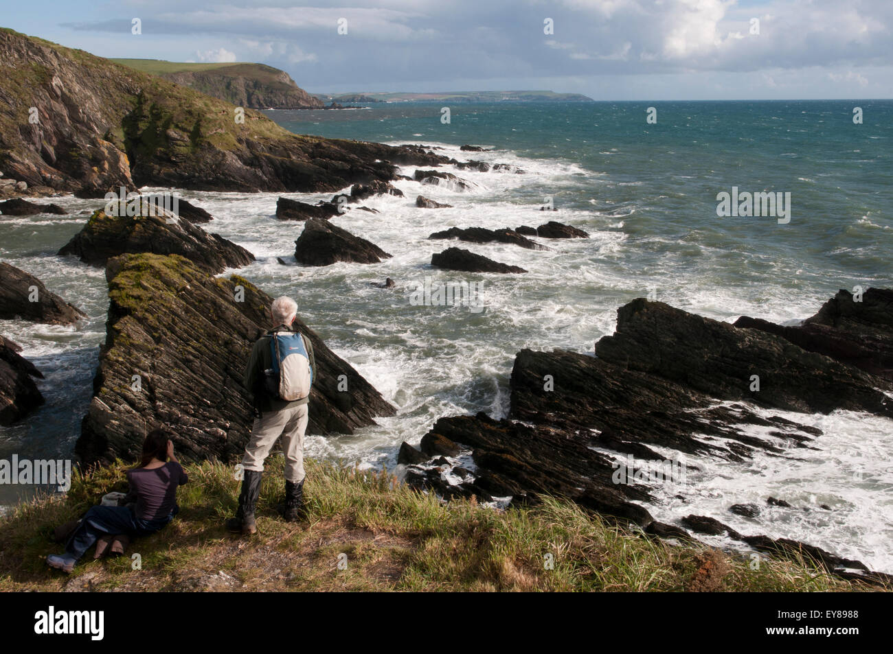 Rear view of people in foreground looking out at rugged coastline Stock ...
