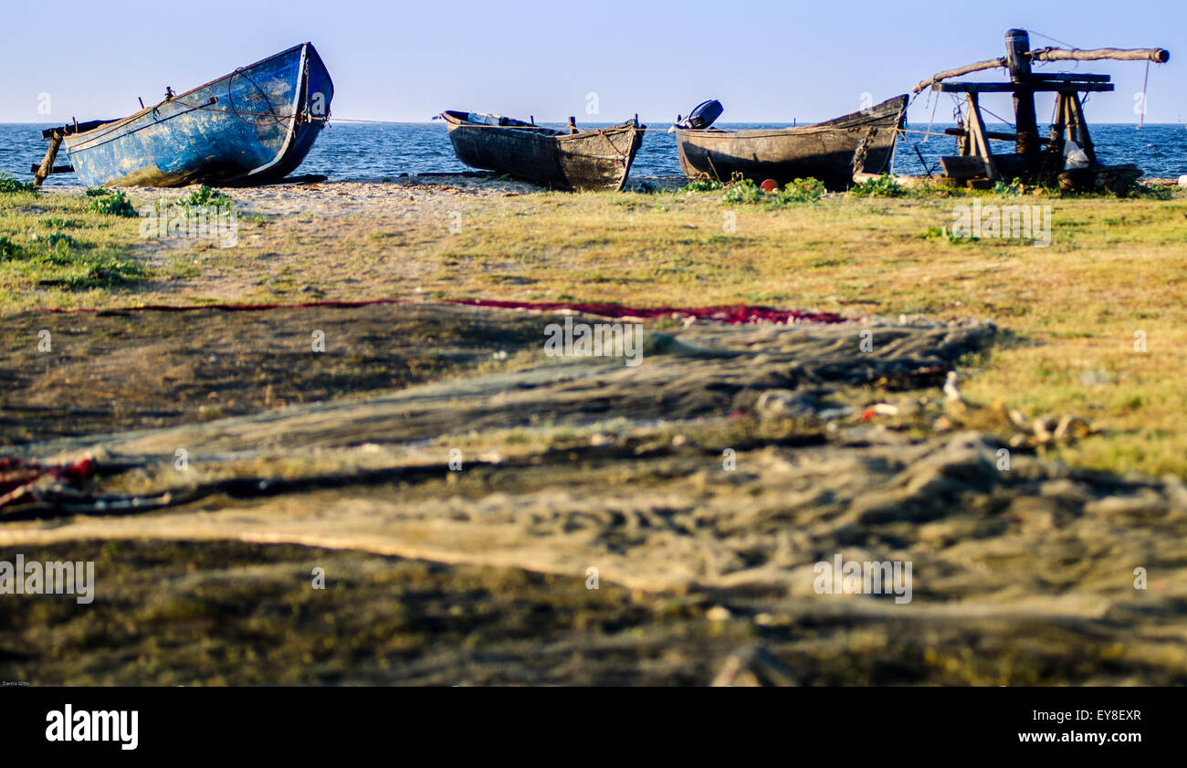 Fishing boats rest on the shore at a serene coastal location under ...