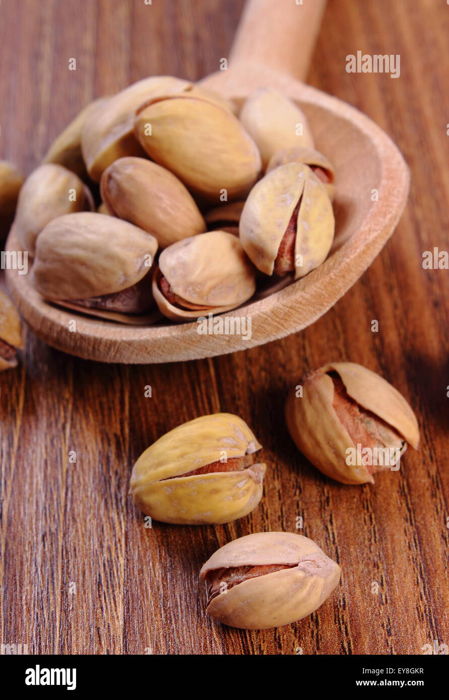 Roasted pistachio nuts with wooden spoon on natural wooden table background, healthy food and ...