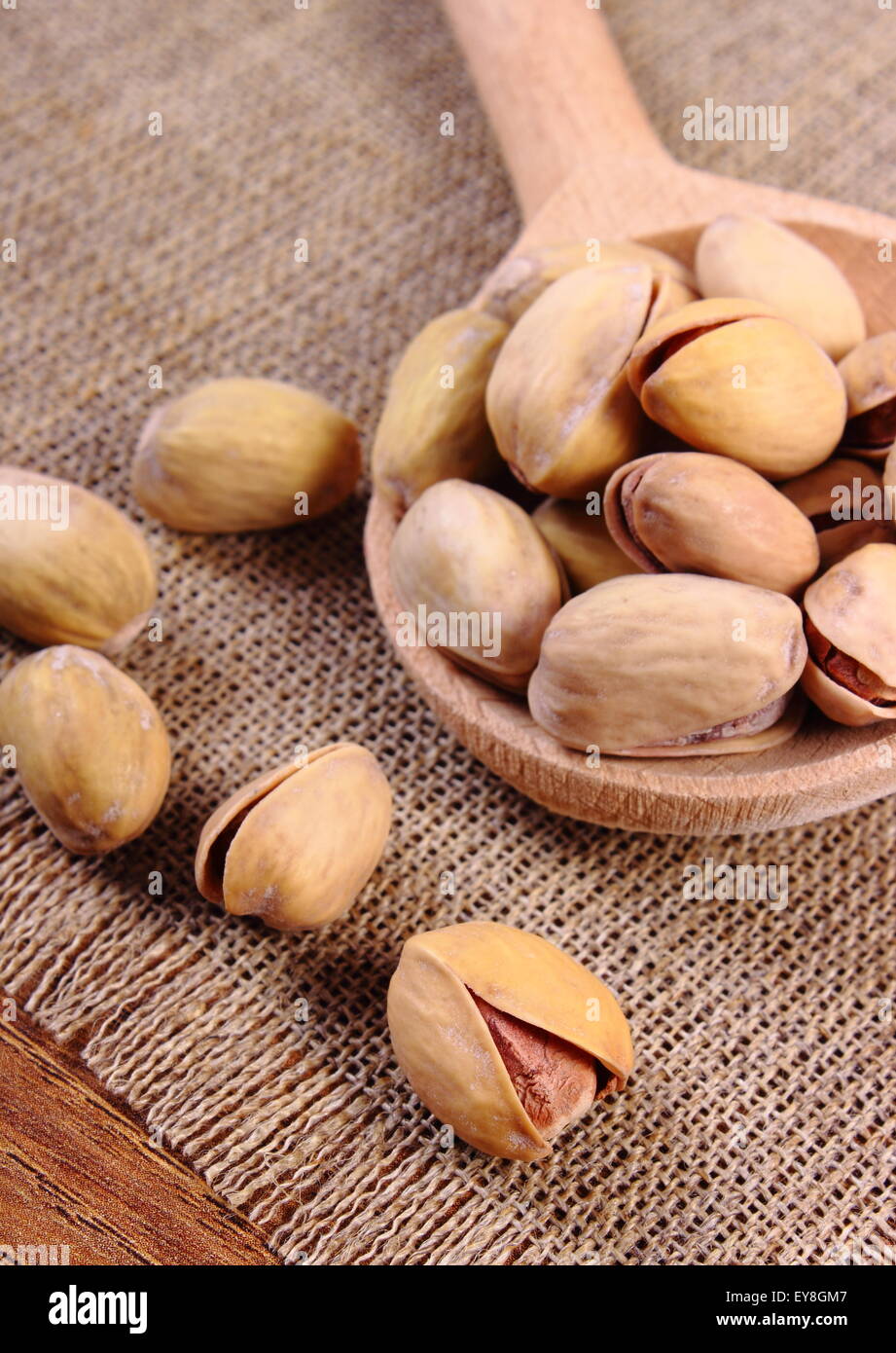 Roasted pistachio nuts with wooden spoon on natural wooden table background, healthy food and ...
