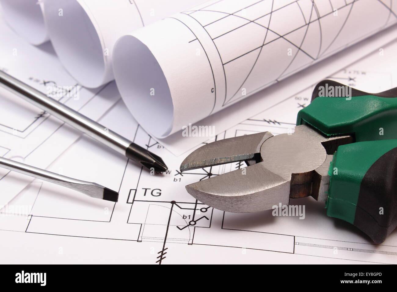 Rolls of diagrams, metal pliers and screwdriver on electrical ...