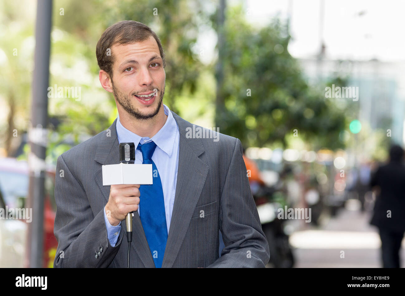 Attractive professional male news reporter wearing grey suit holding ...