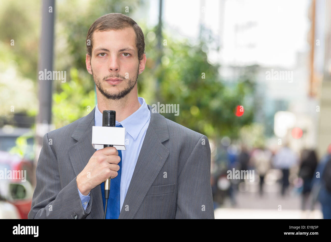 Attractive professional male news reporter wearing grey suit holding ...