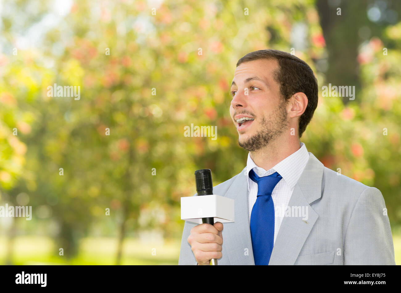 Successful handsome male news reporter wearing light grey suit working ...