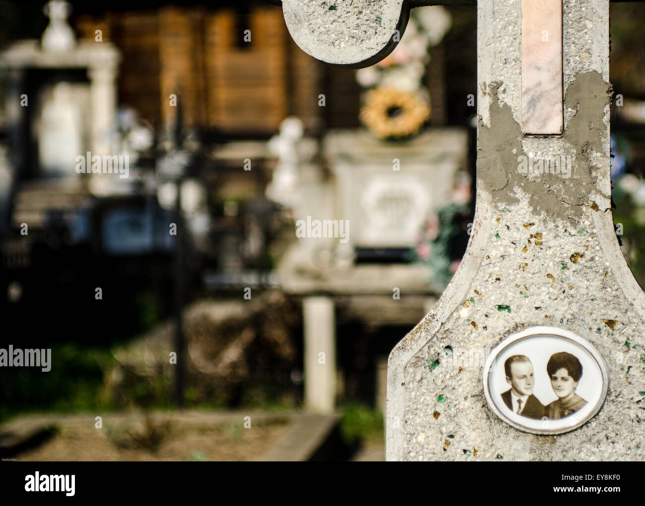In a serene cemetery, a weathered cross marks the resting place Surrounding gravestones create a ...