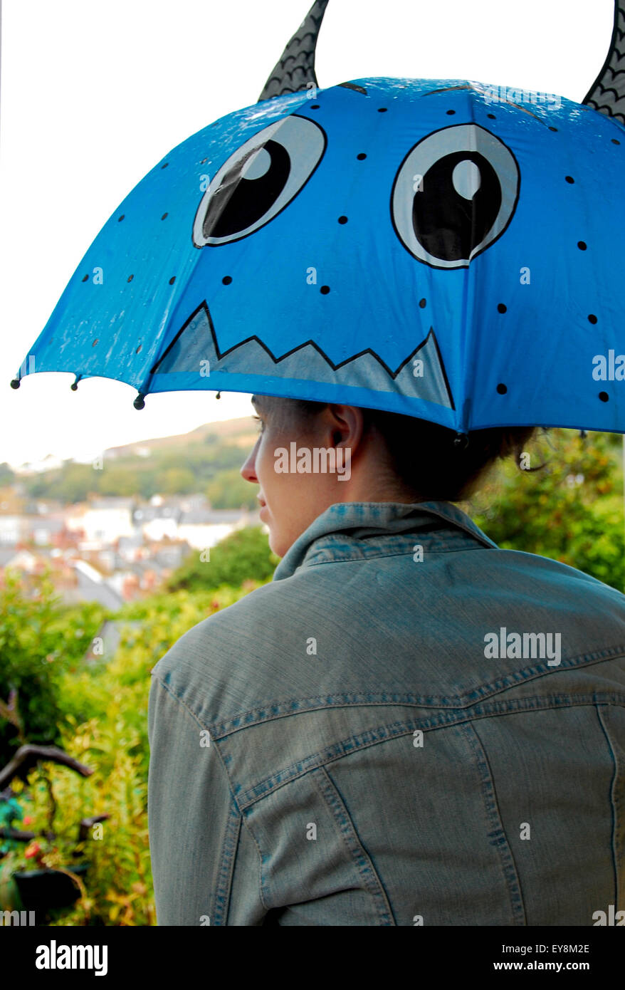 A young woman looks out at the driving rain, from the cover of her sad ...
