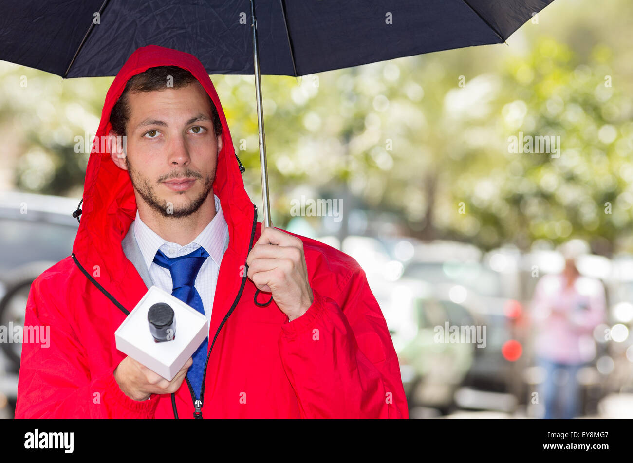 Successful handsome male journalist wearing red rain jacket working in ...