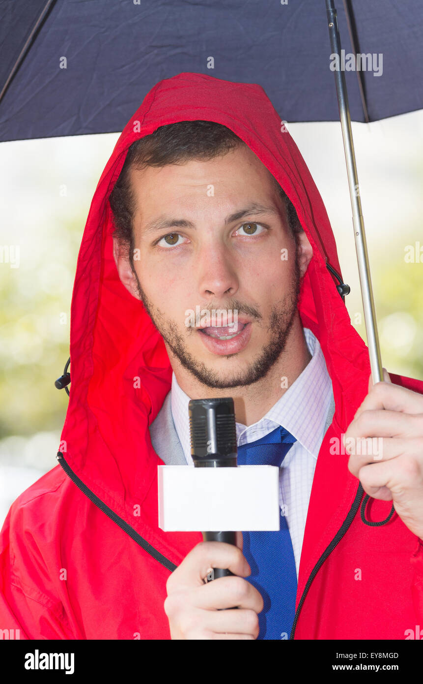 Successful handsome male journalist wearing red rain jacket working in ...