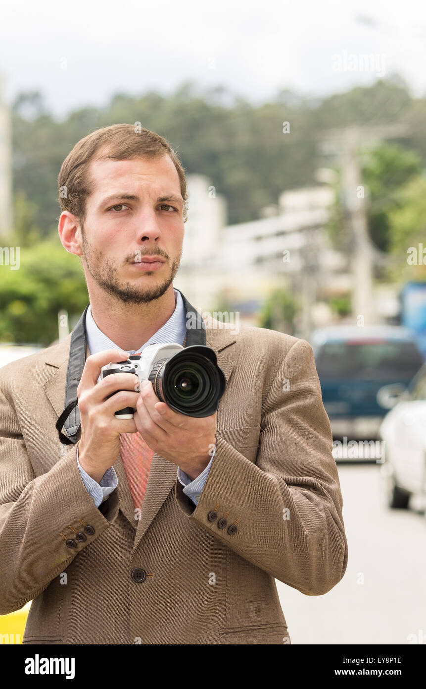 Successful attractive male photographer wearing brown suit working ...