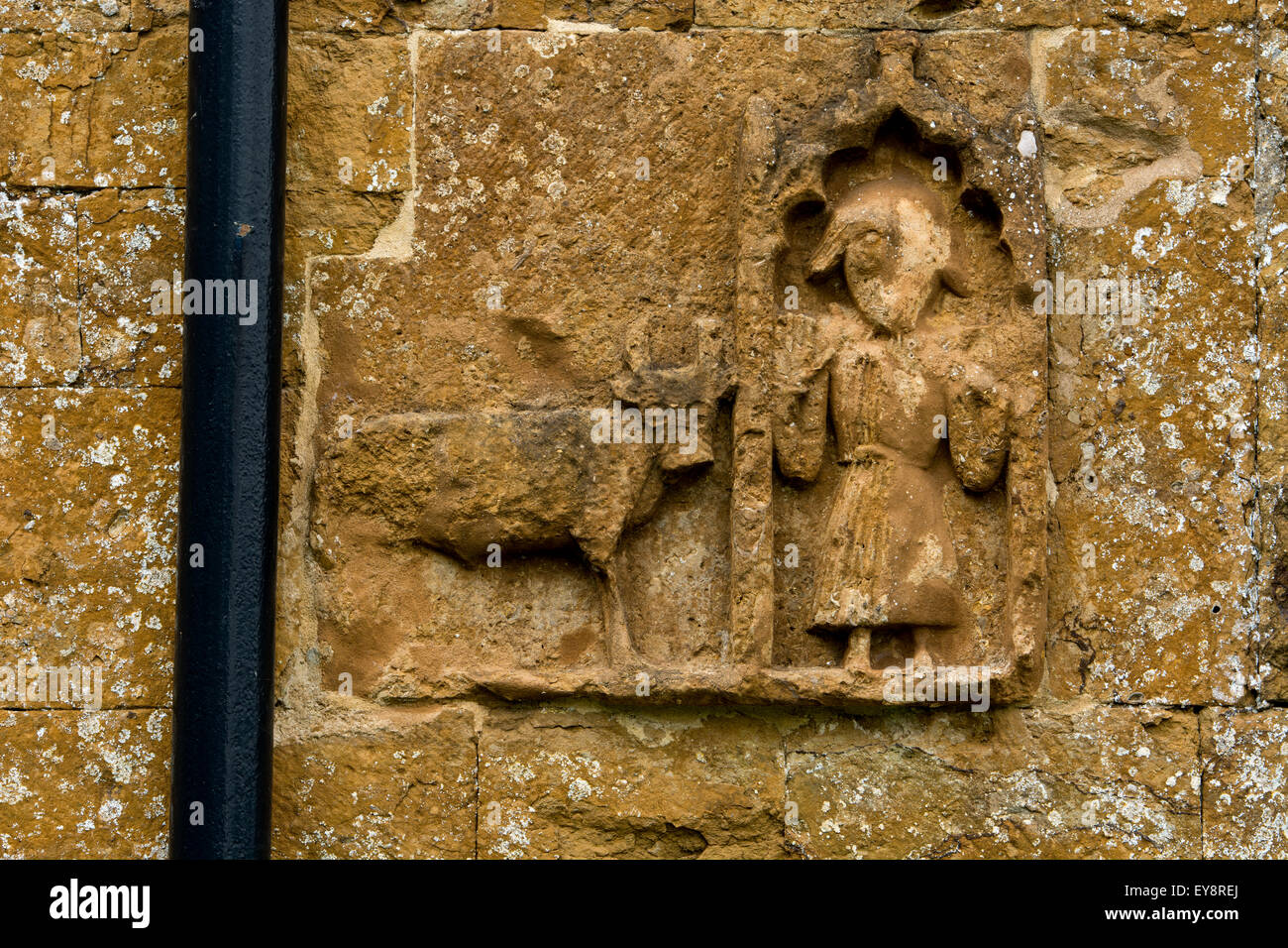 Carving of a man and a cow on outside wall of Holy Trinity Church ...