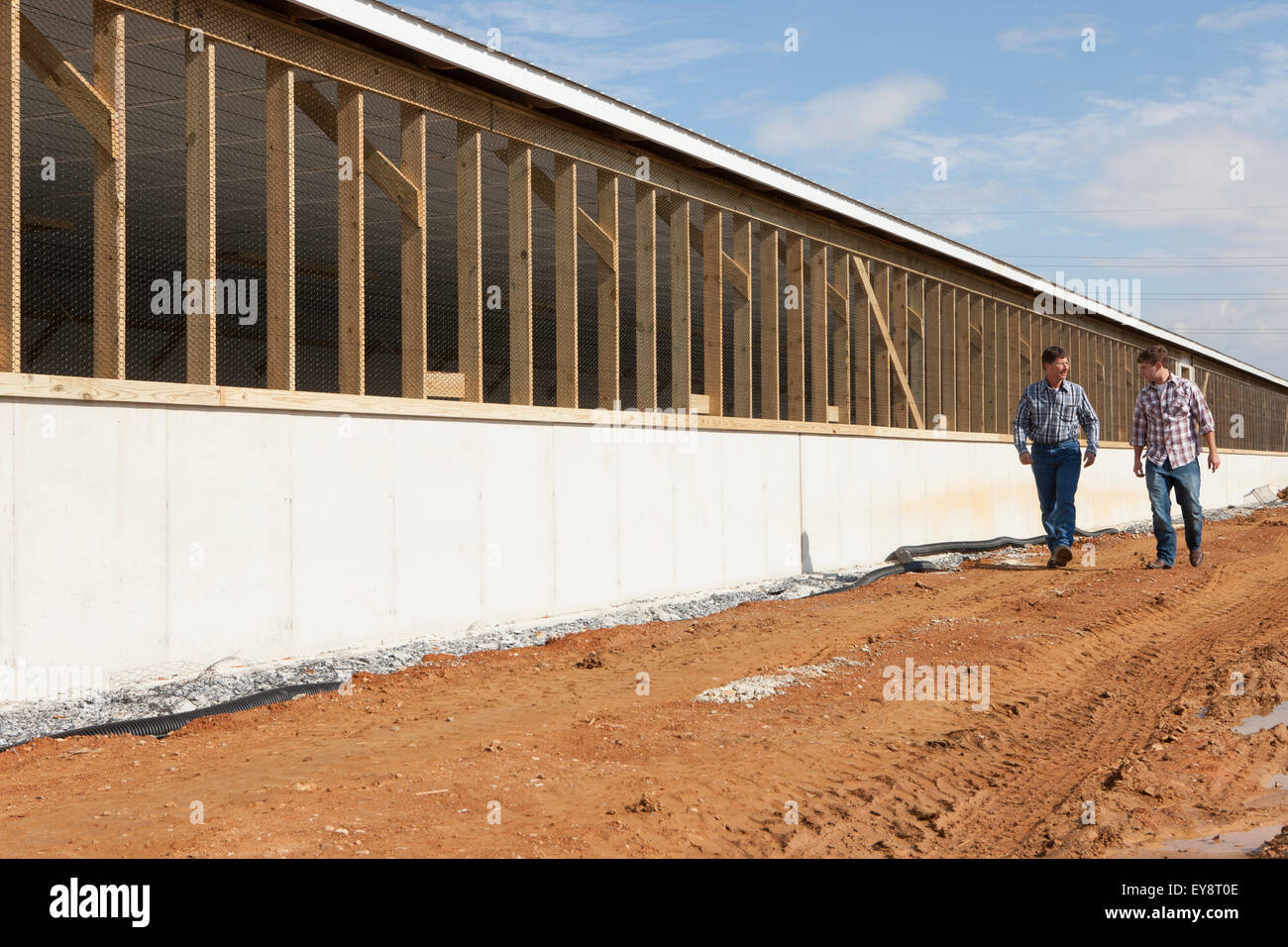 Father and son walk perimeter of new barn inspection construction ...