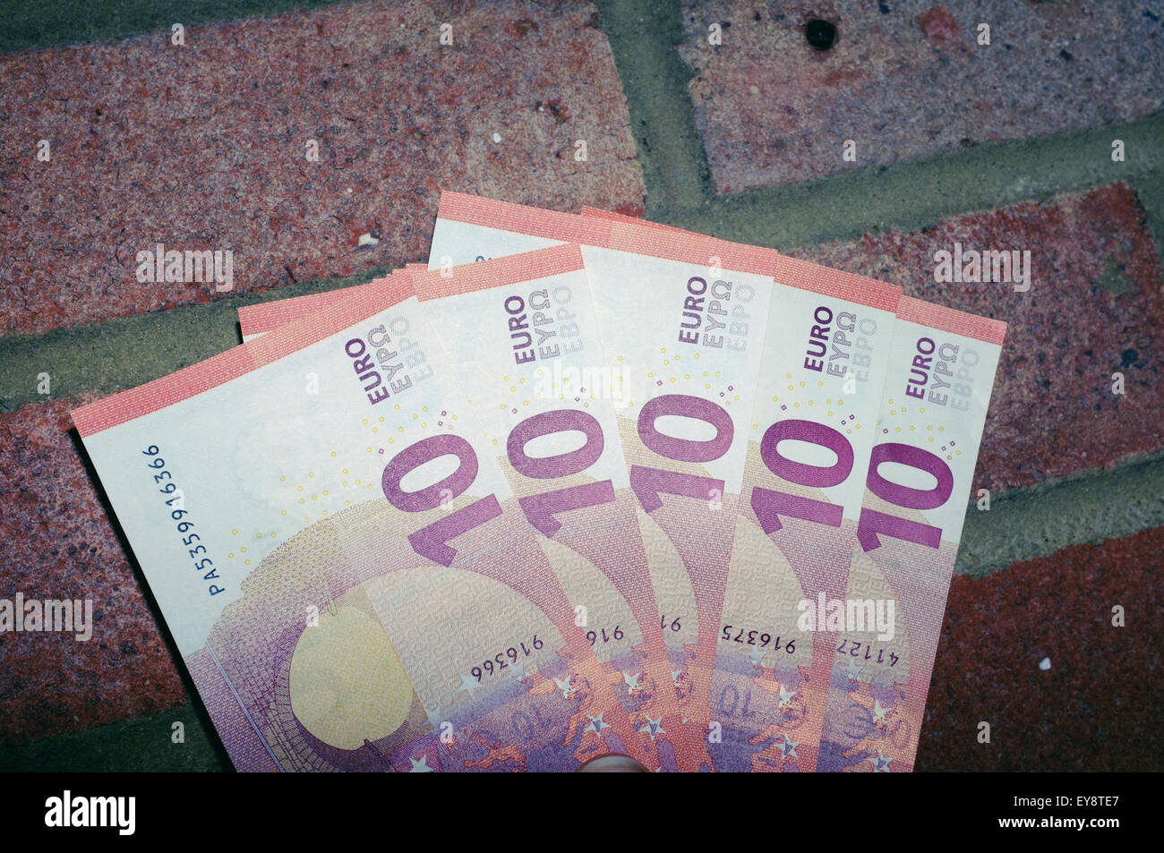 10 Euro notes held against a brick wall Stock Photo - Alamy