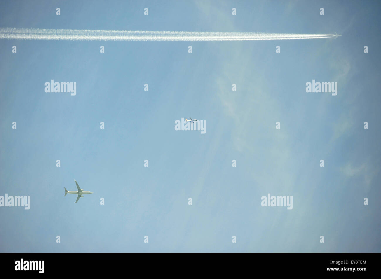 Three passenger planes leave trails against a blue sky Stock Photo - Alamy