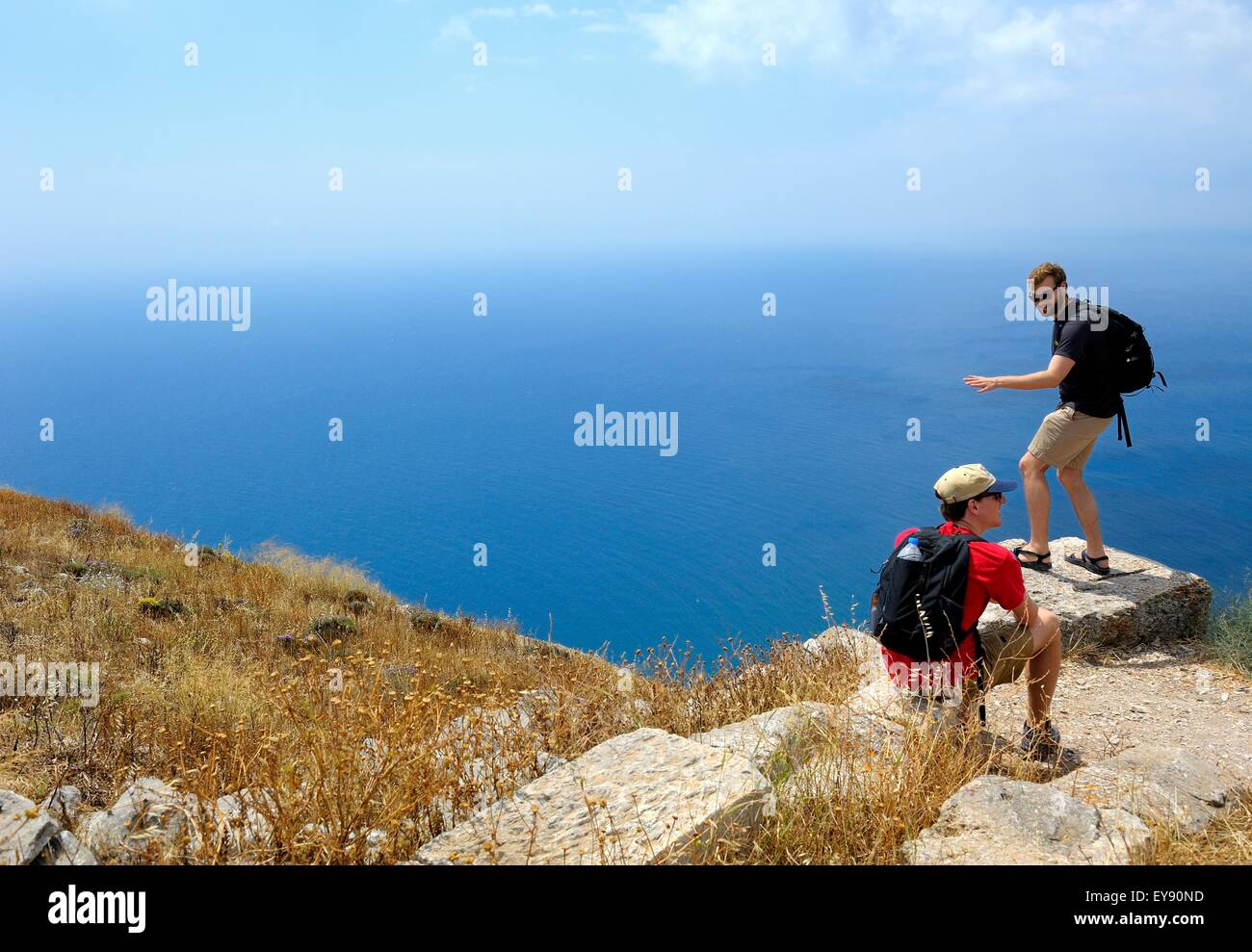 Tourists balancing on a rock at the top of Messa Vouno mountain Kamari ...