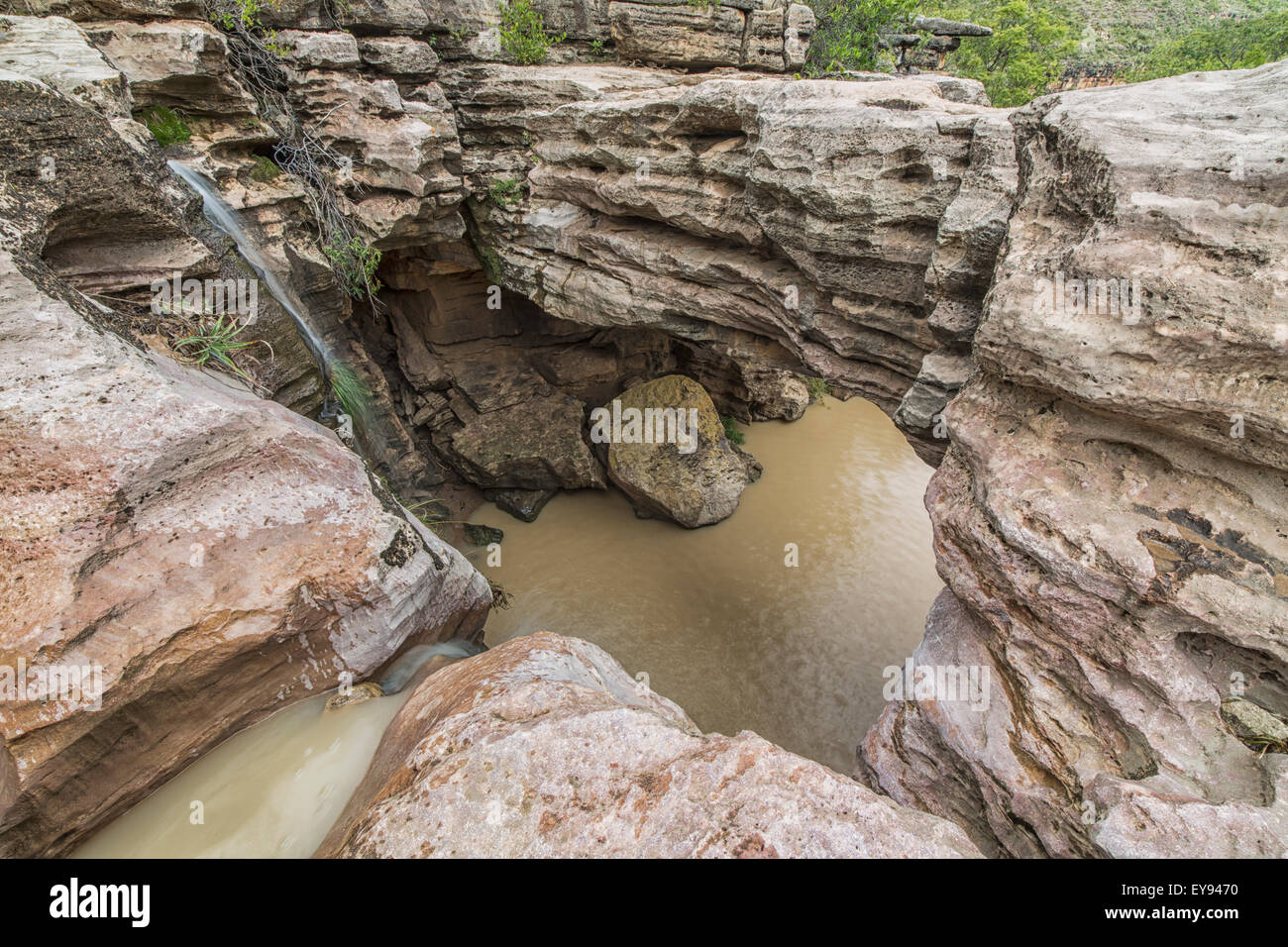 Uniquely carved rocks and a natural bridge around an unnamed waterfall ...
