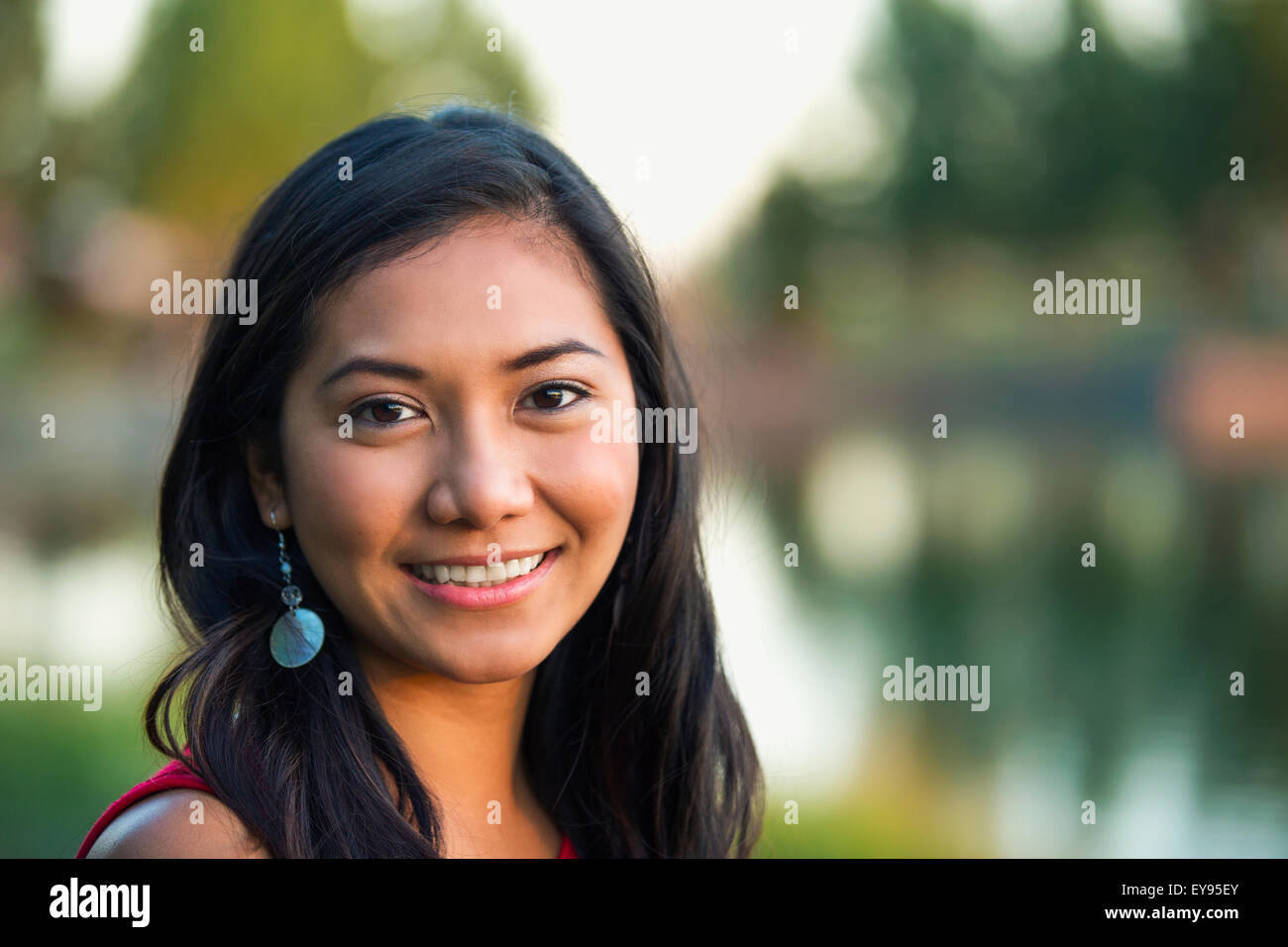 Portrait of a beautiful young Filipino woman smiling in a city park in ...