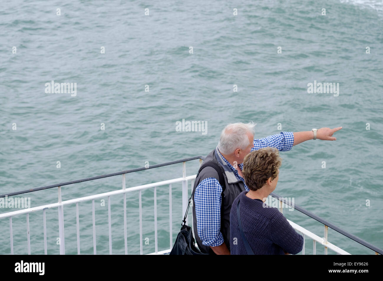 middle aged male and female standing on the deck of a ferry with the ...