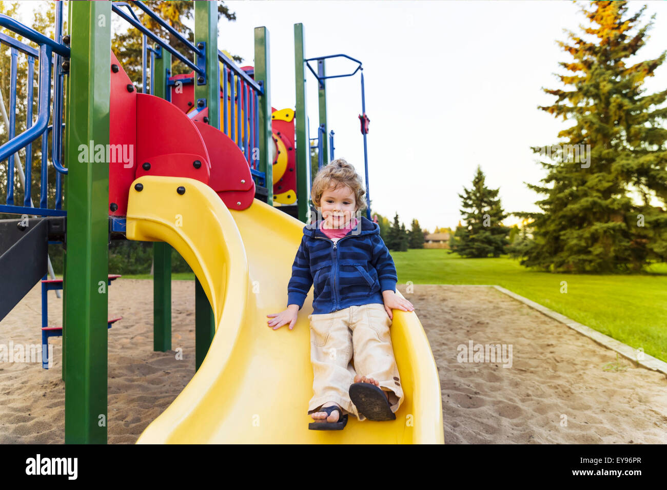 Toddler boy playing at a city playground at sunset; St. Albert, Alberta ...