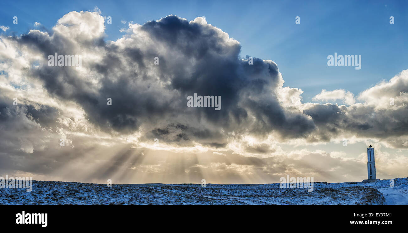 Rays of light shine out from behind the clouds in the skies above a ...