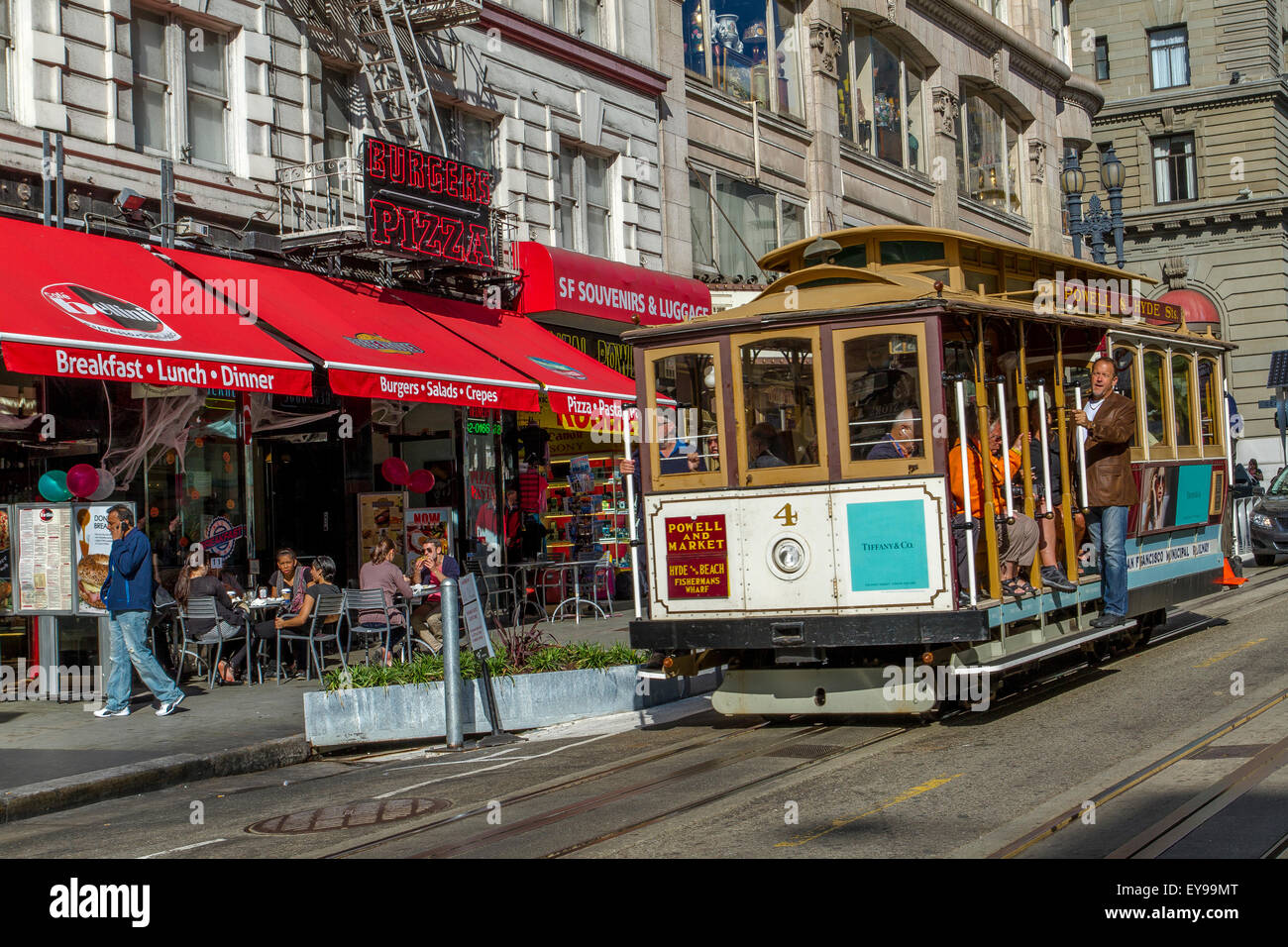 A man rides a cable car standing outside on the running board down a ...