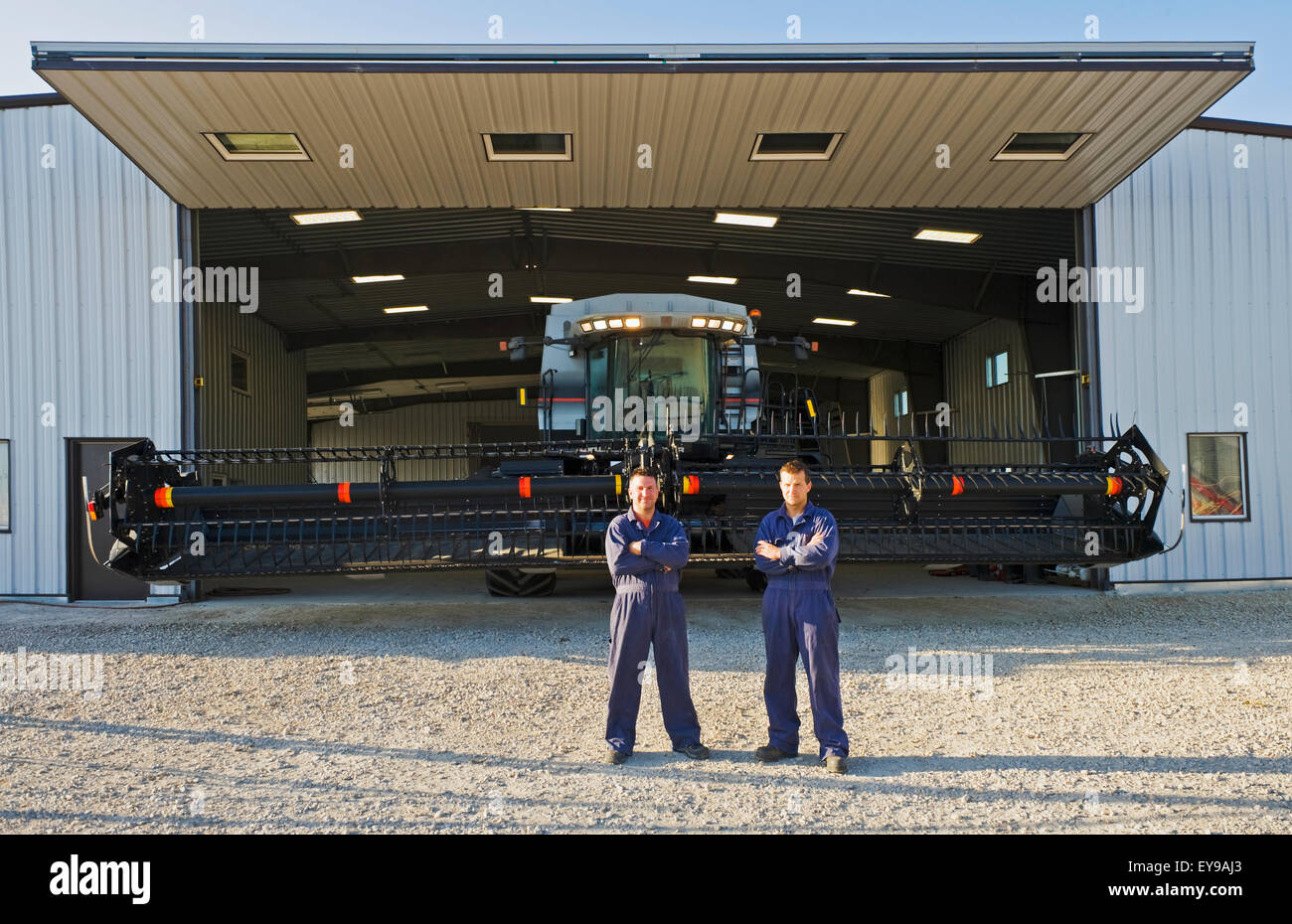 Farmers next to his combine parked in front of the farm repair shop ...