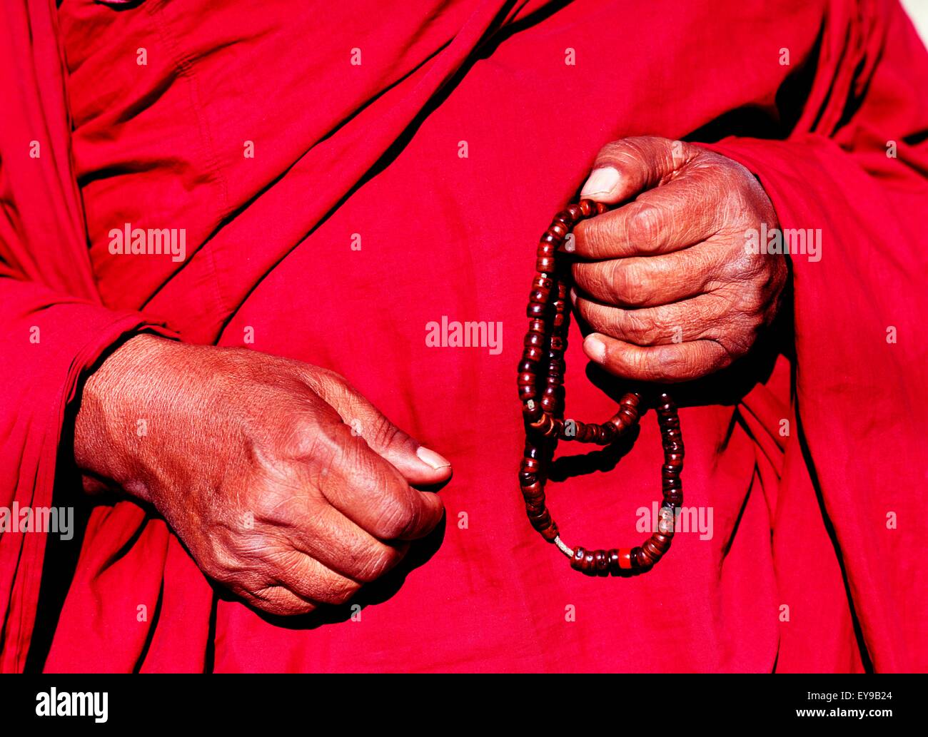 Monk In Red Robe Holding Prayer Beads Stock Photo - Alamy