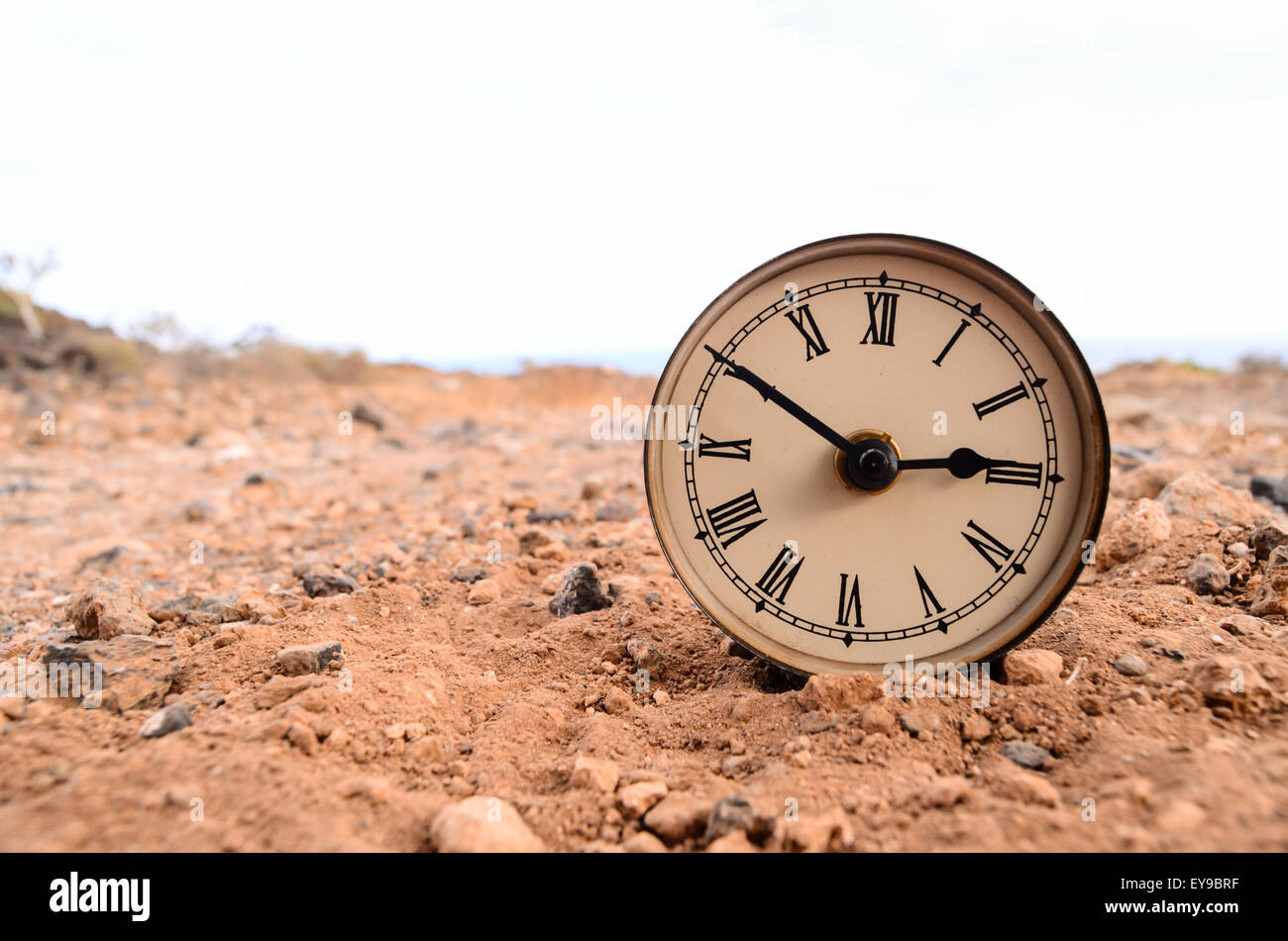 Classic Analog Clock In The Sand Stock Photo - Alamy
