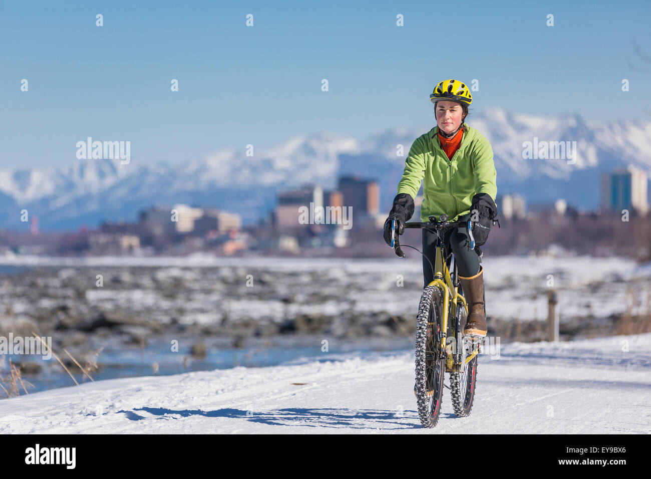 A Young Woman rides a studded tire bicycle down the Tony Knowles ...
