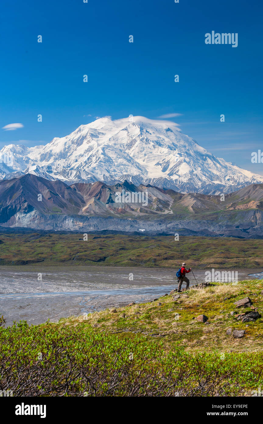Hiker on a hillside in front of Mt. McKinley and Muldrow Glacier ...