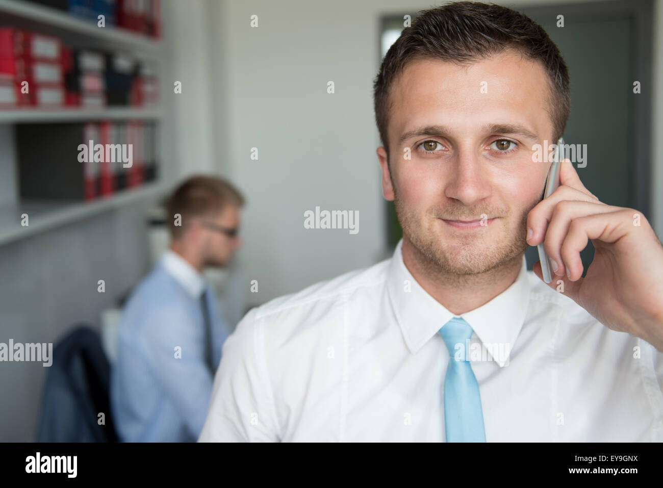 Happy Young Business Man Talking On Telephone In Modern Office Behind ...