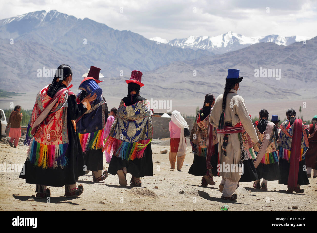 People In Traditional Dress And Hats Walking Below Mountains Stock ...