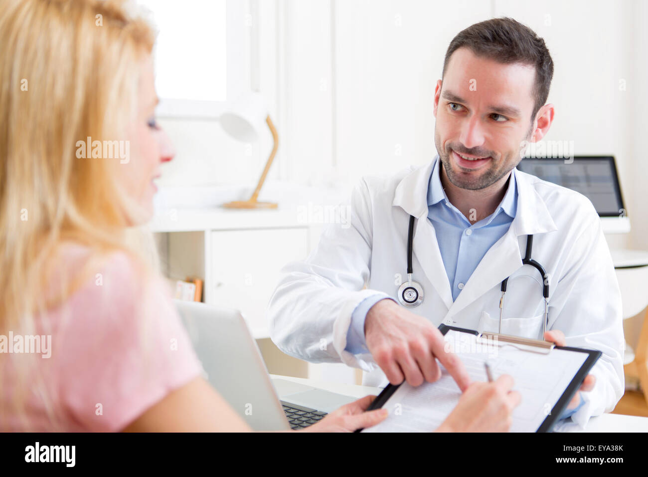 View of a Patient signing the document of a young attractive doctor ...