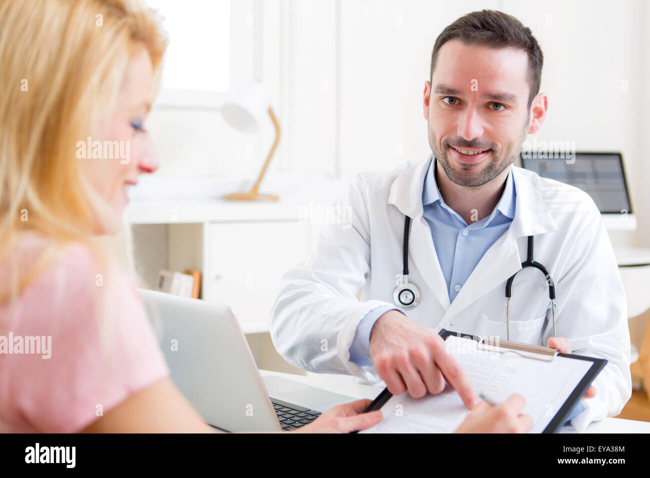 View of a Patient signing the document of a young attractive doctor ...