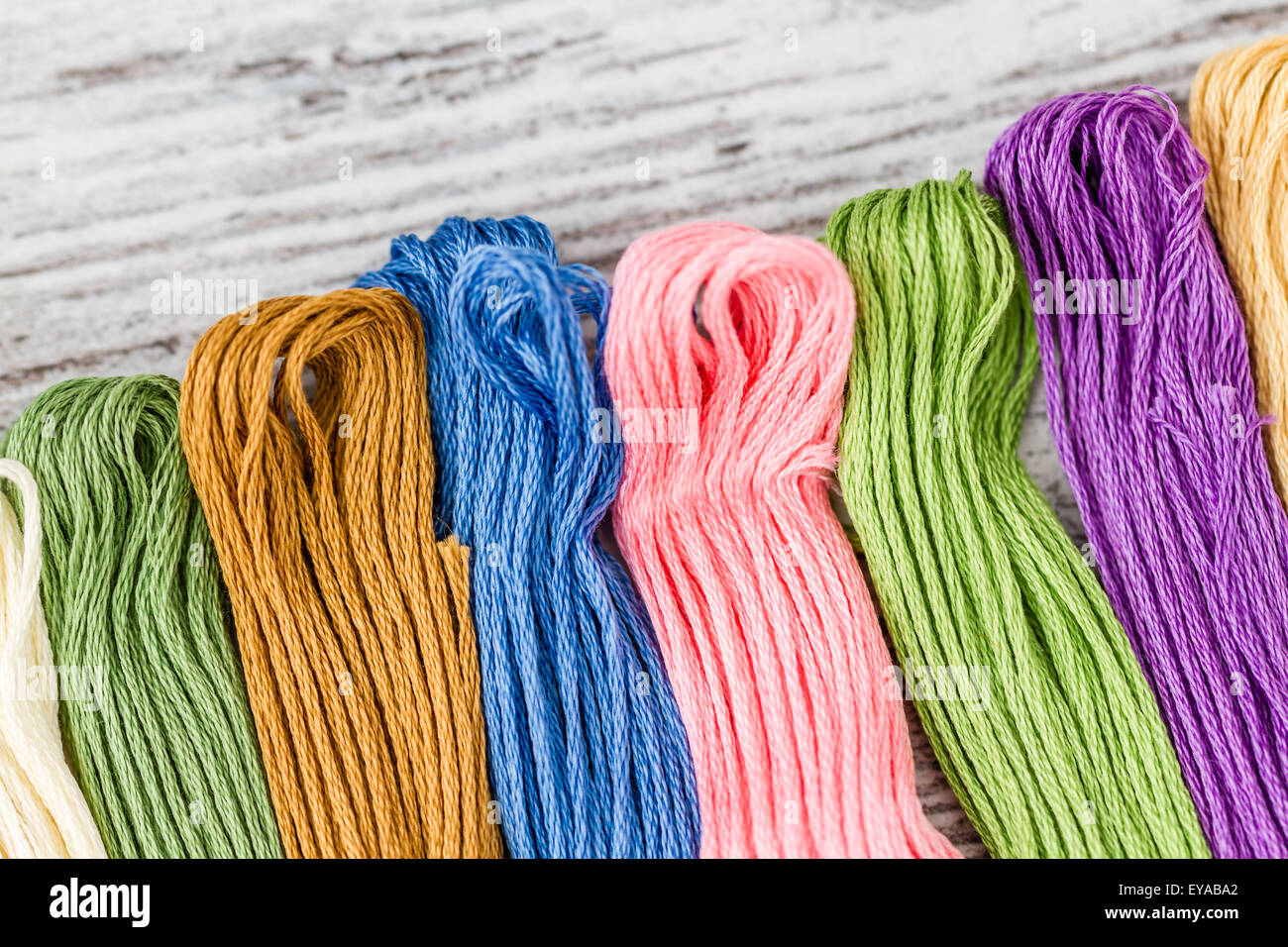 Threads for embroidery from different colors on white wooden background ...